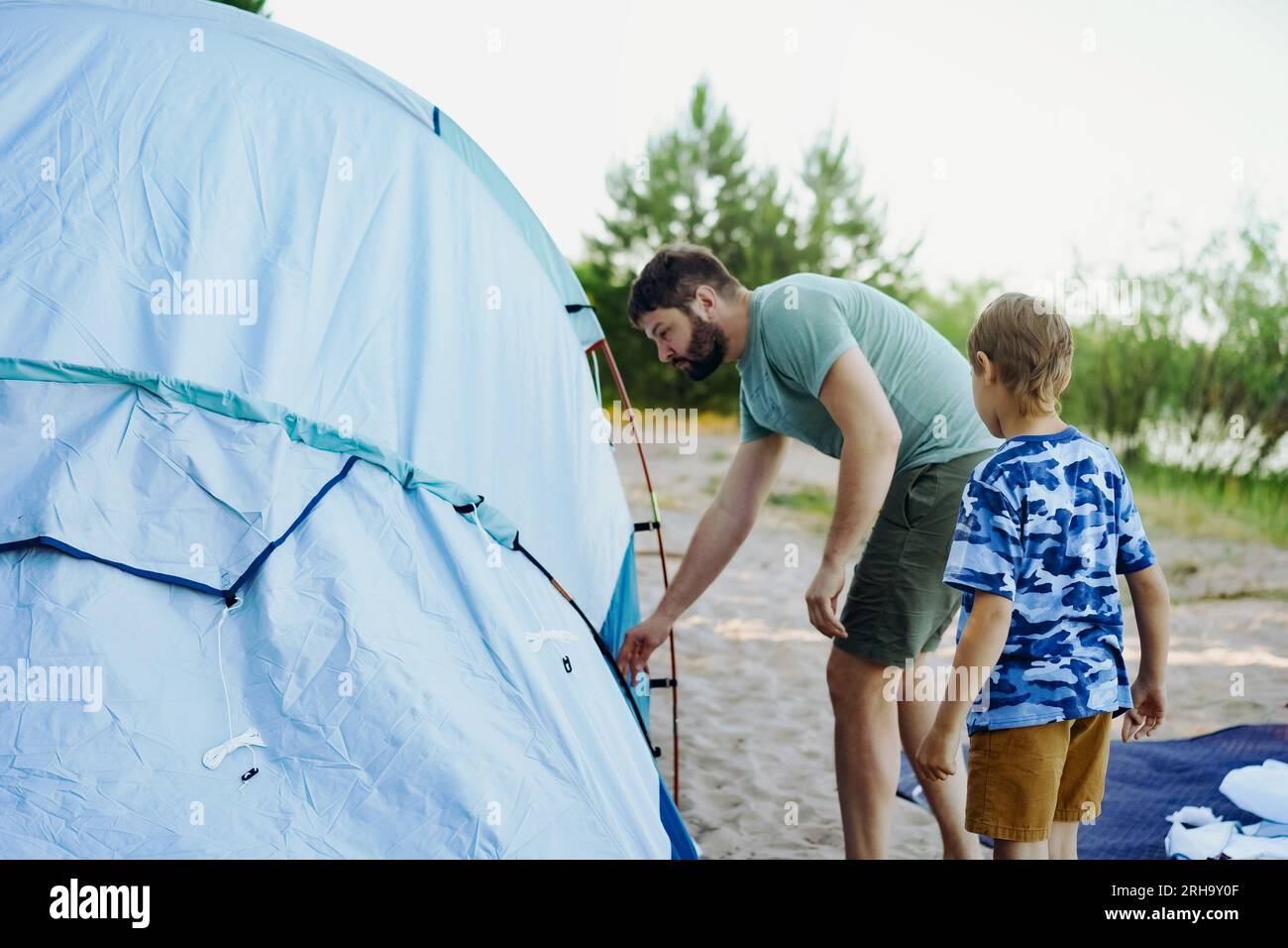 cute little caucasian boy helping father to put up a tent. Family camping and local travelling ...