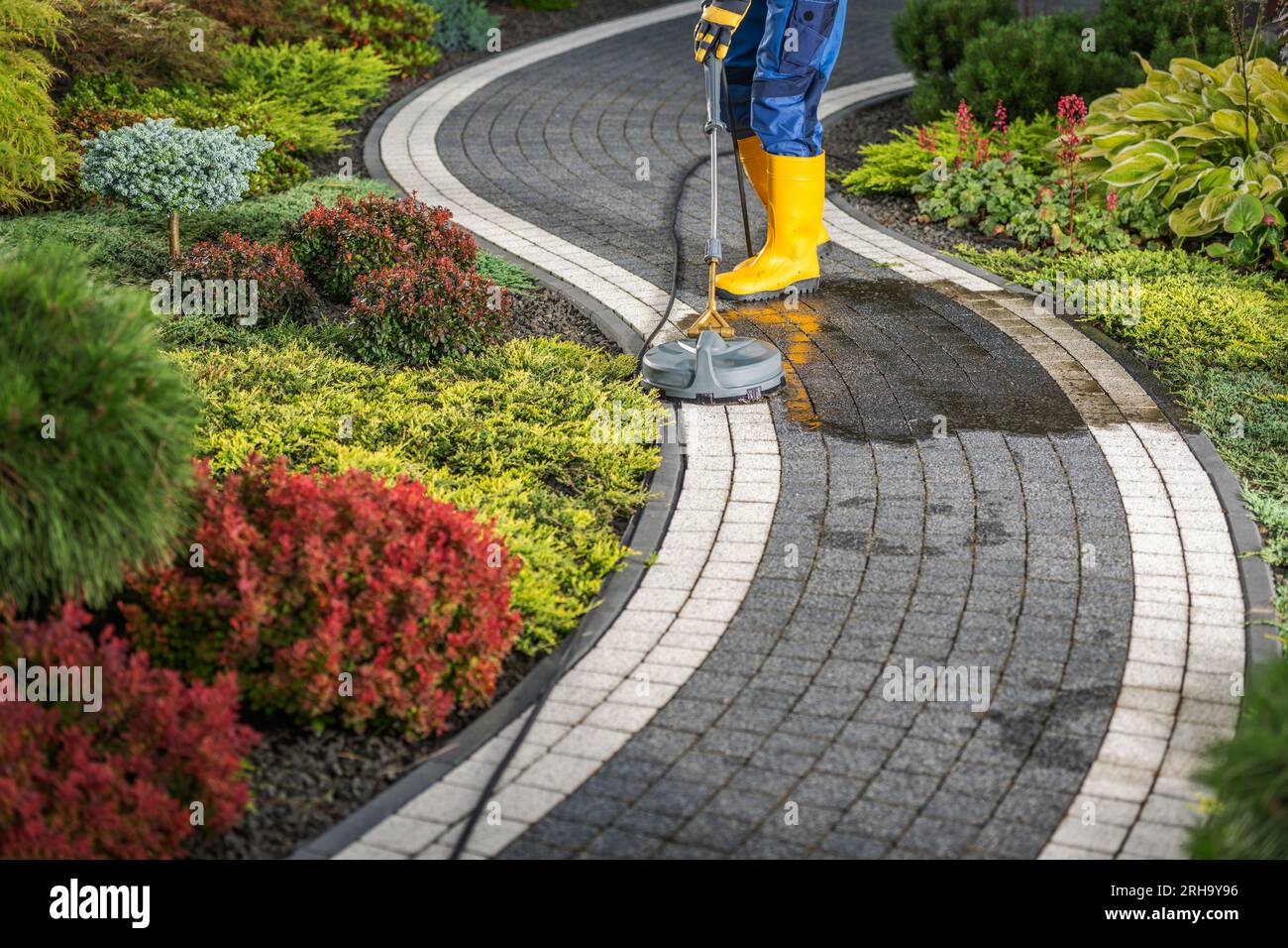Worker Power Washing Residential Garden Pathway Using Professional ...