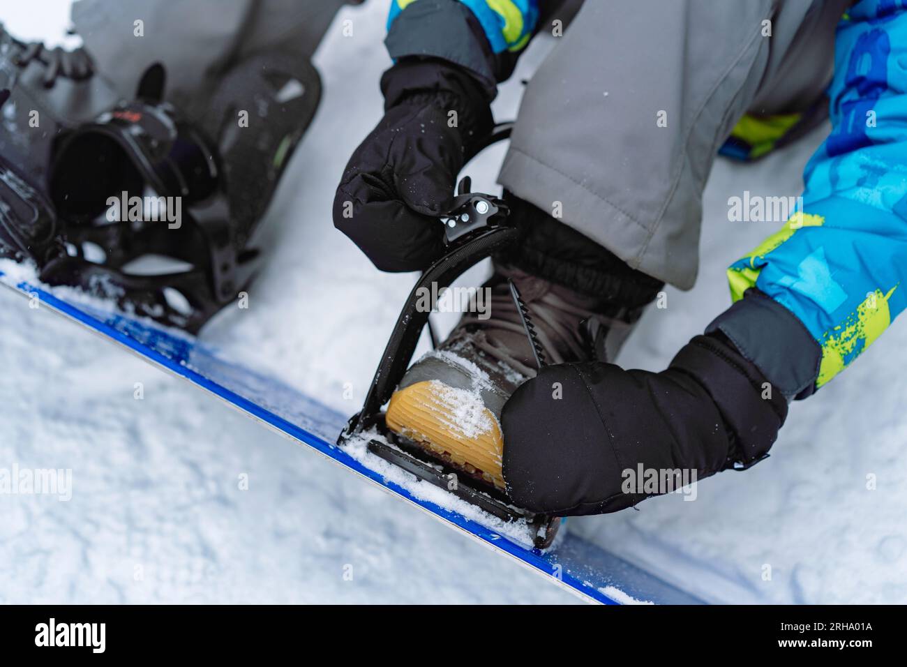 close up vie of little boy sitting on snow putting his feet in ...