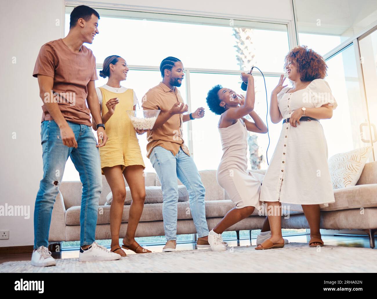 Karaoke, entertainment and friends singing in the living room with a ...