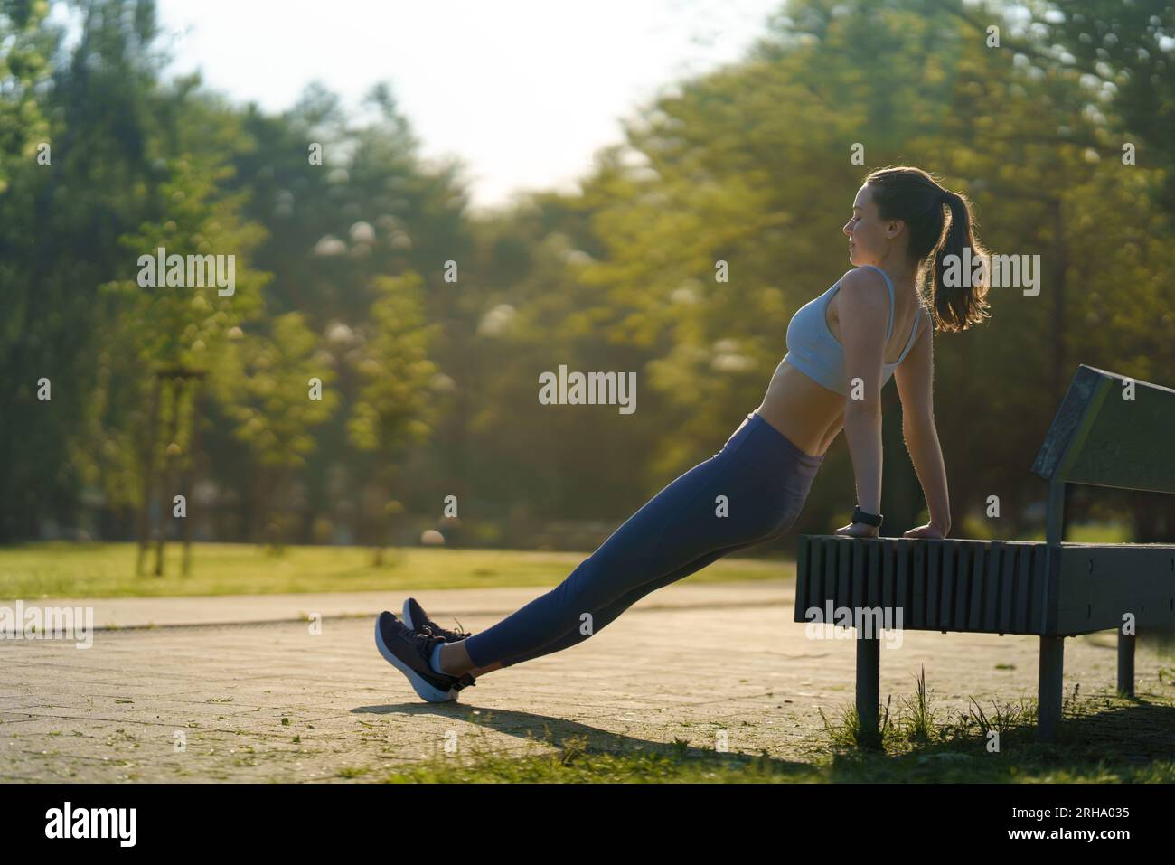 Full lenght portrait of beautiful fitness woman doing park bench push ...