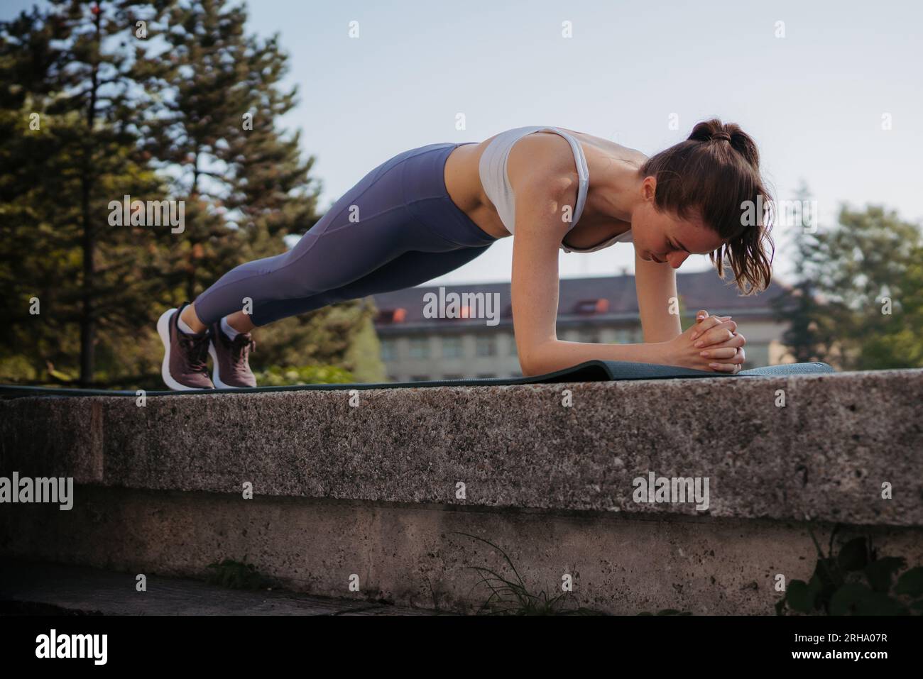 Side view of young sporty woman doing plank excercise on gym mat in the ...