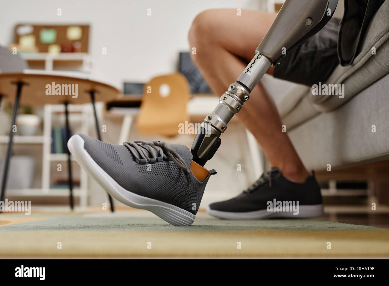 Closeup of unrecognizable man with bionic prosthetic leg at home ...