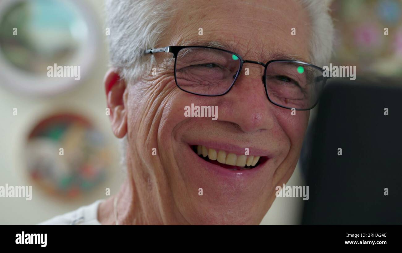 Happy senior man laughing and smiling while staring at computer screen ...