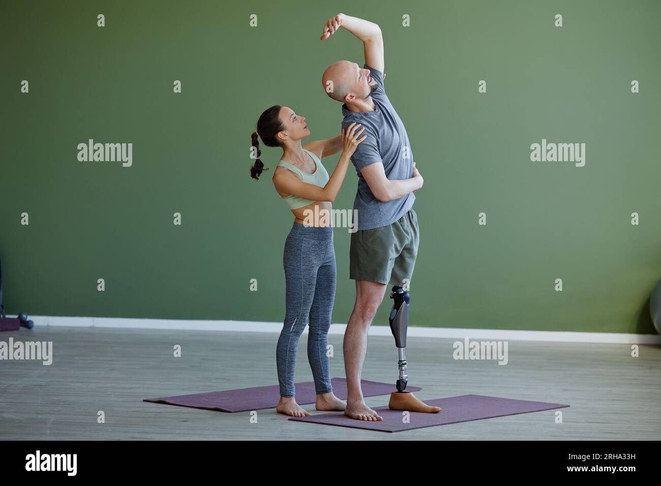 Adult man with prosthetic leg doing exercises indoors with woman ...