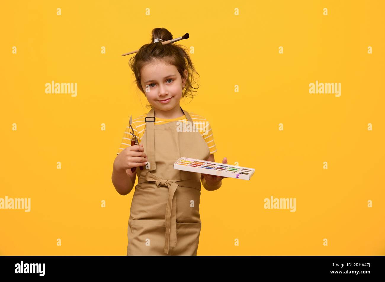 Studio portrait beautiful little girl, painter artist smiles looking at ...