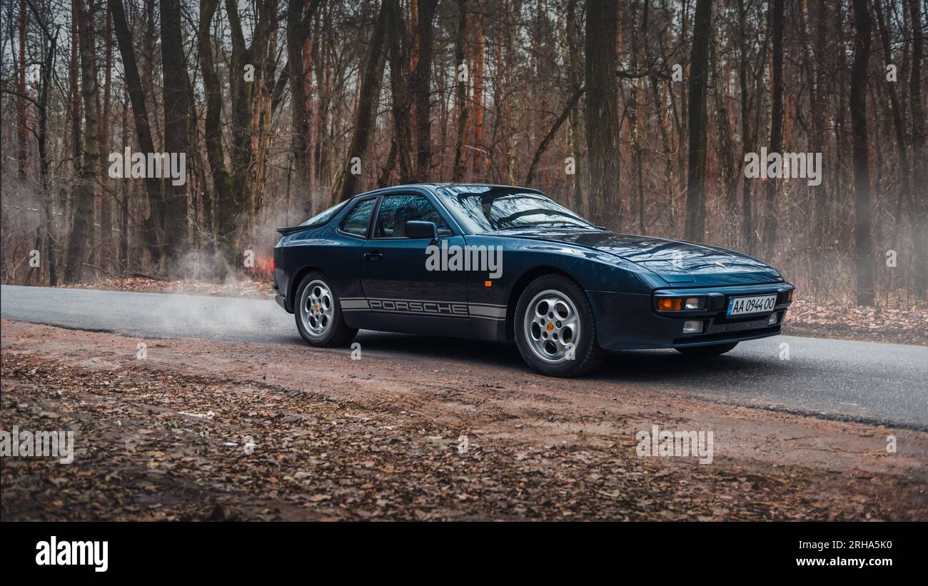 dark blue Porsche 944 in autumn forest. Front three quarter view of ...