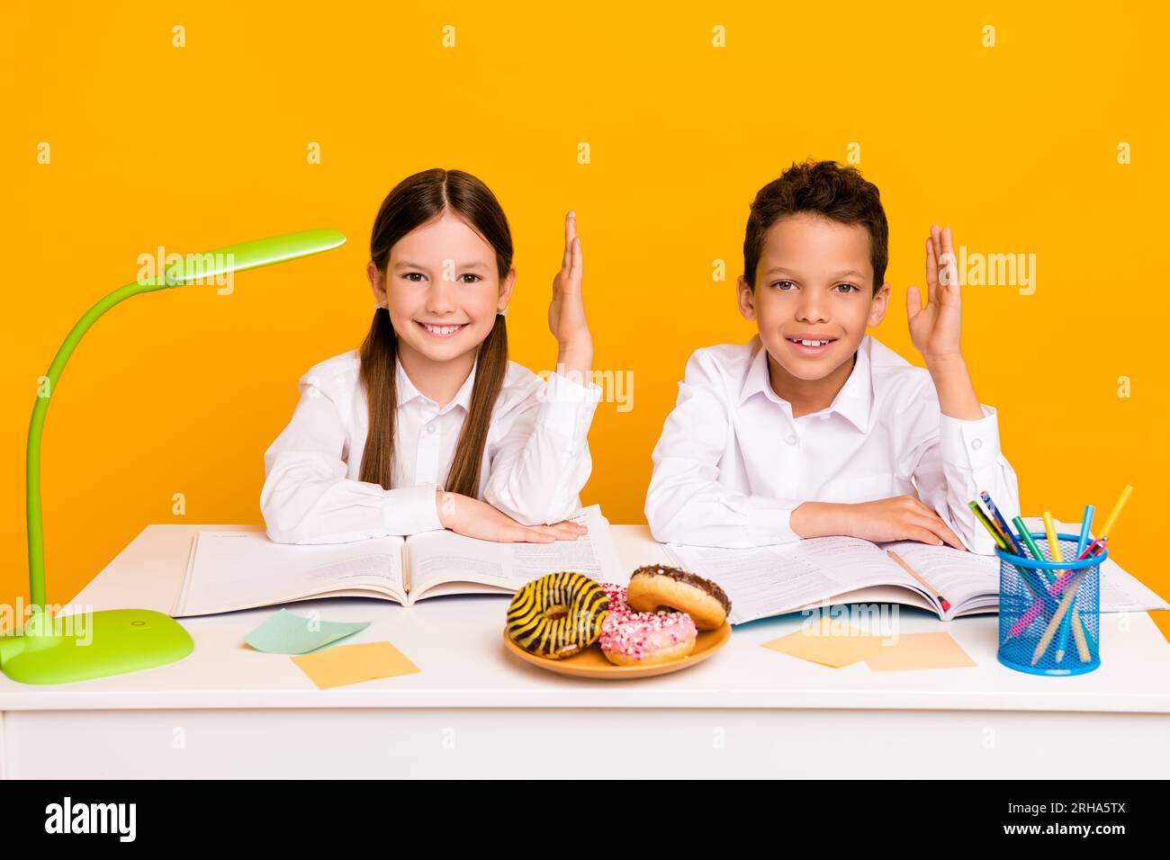 Photo of two bright smart schoolchildren raise hands up answer teacher ...