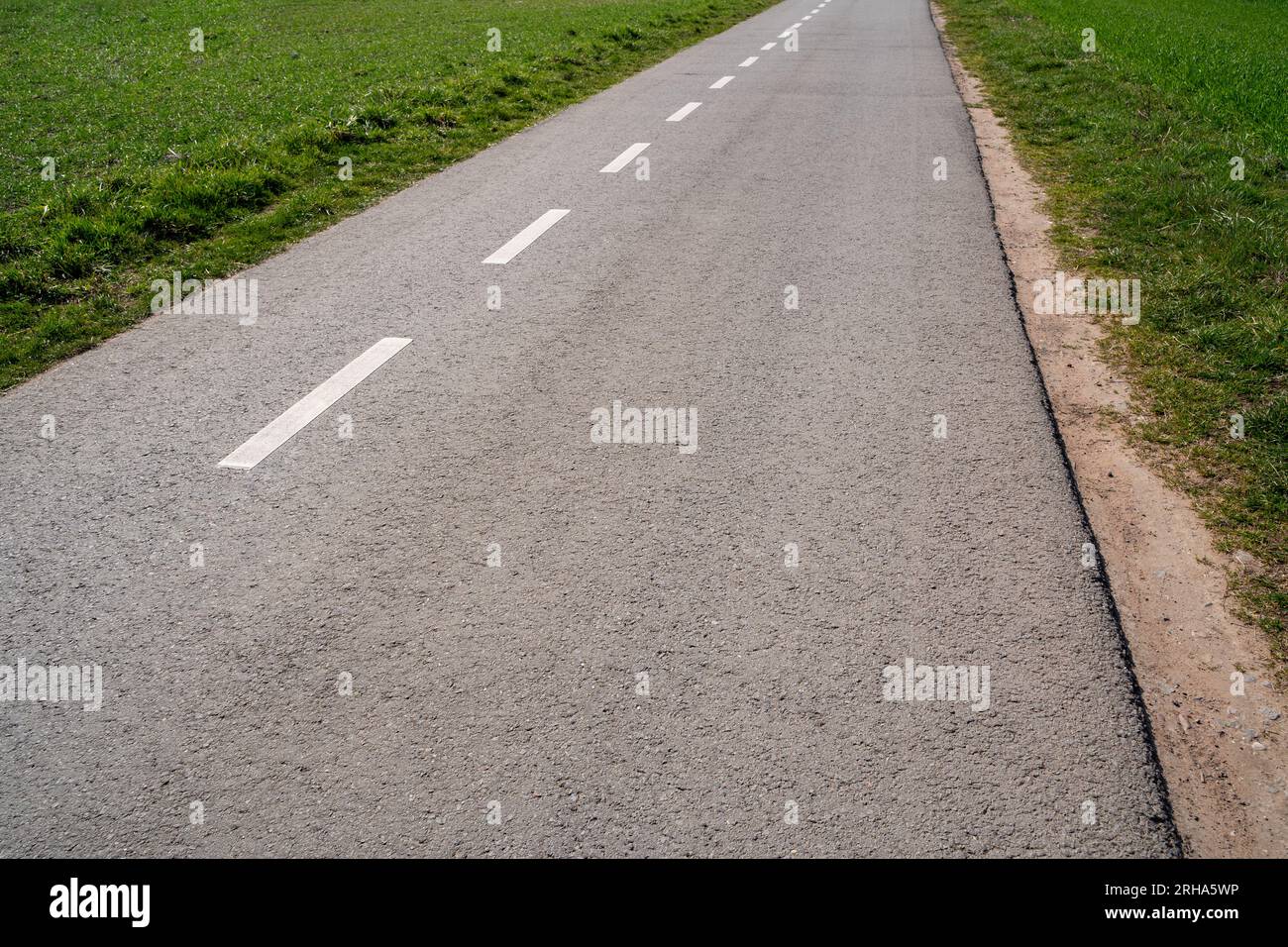 Rural asphalt road with white stripes between grass in the countryside ...