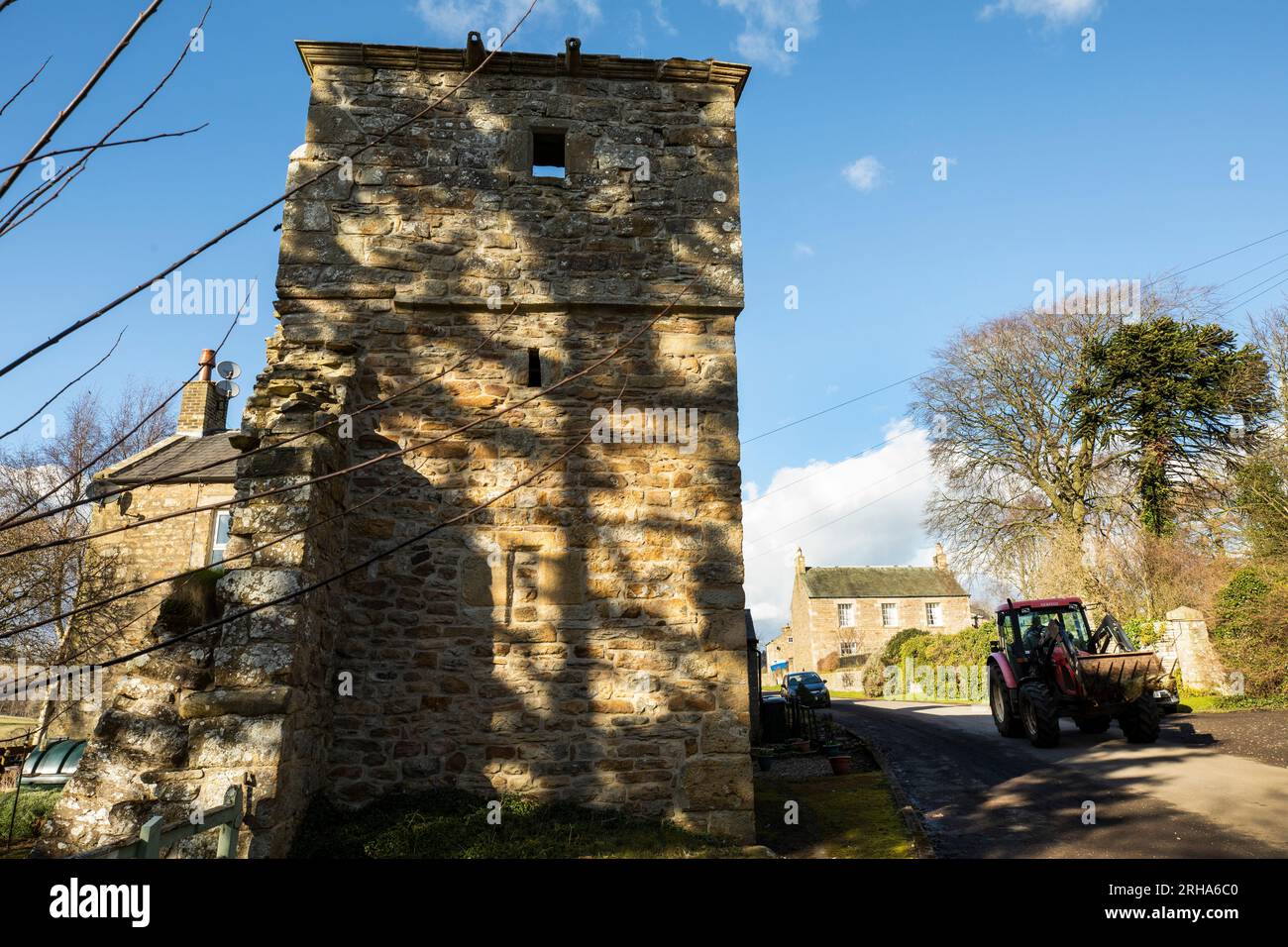 A tractor passing through the hamlet of Ninebanks near Alston showing Ninebanks Tower, a 16th ...