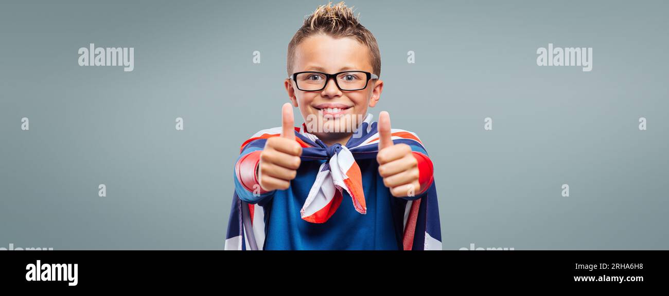 Smiling cute superhero thumbs up, he is wearing a British flag as a ...