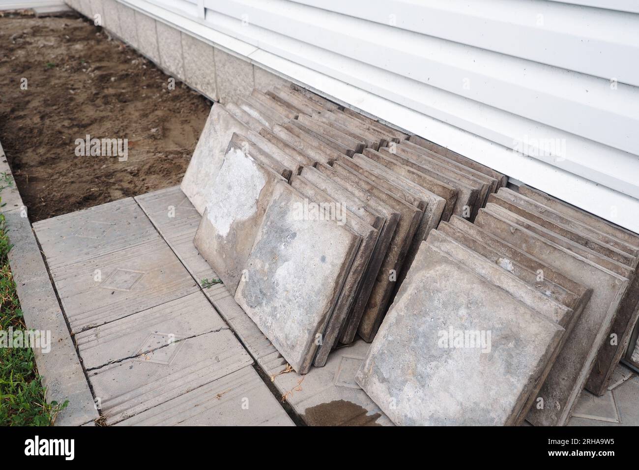 Facing concrete tiles lie on ground in stack. Replacing building ...