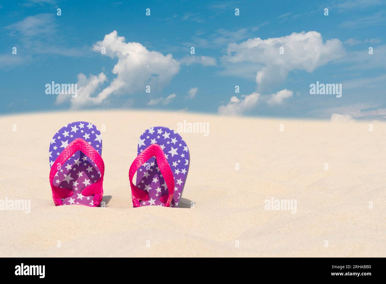Slippers lie in the sand on the beach against the blue sky. Summer ...