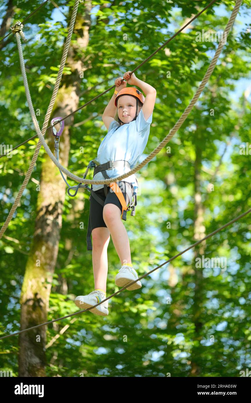 Portrait of child girl having fun at outdoor extreme adventure rope ...
