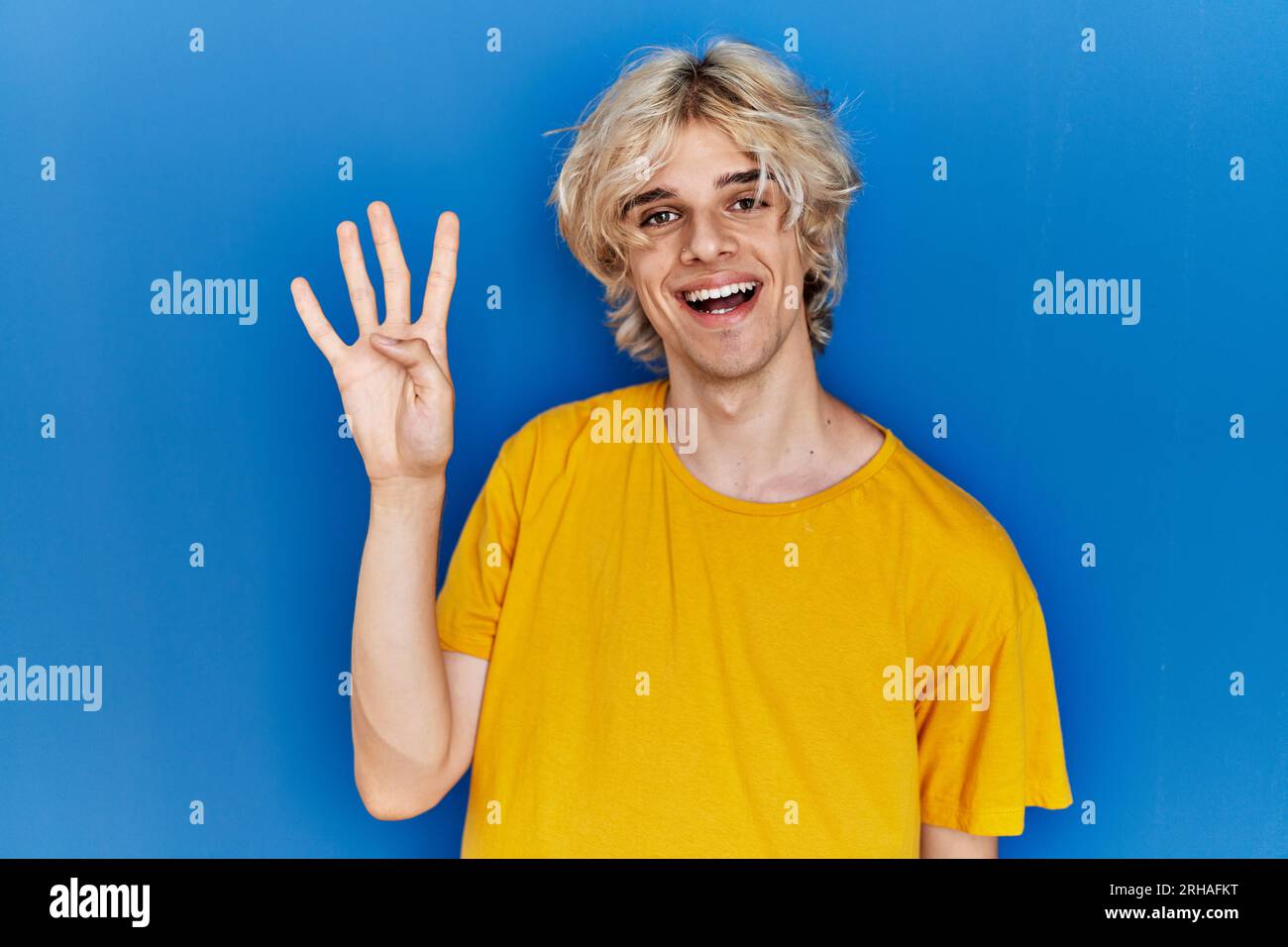 Young modern man standing over blue background showing and pointing up ...