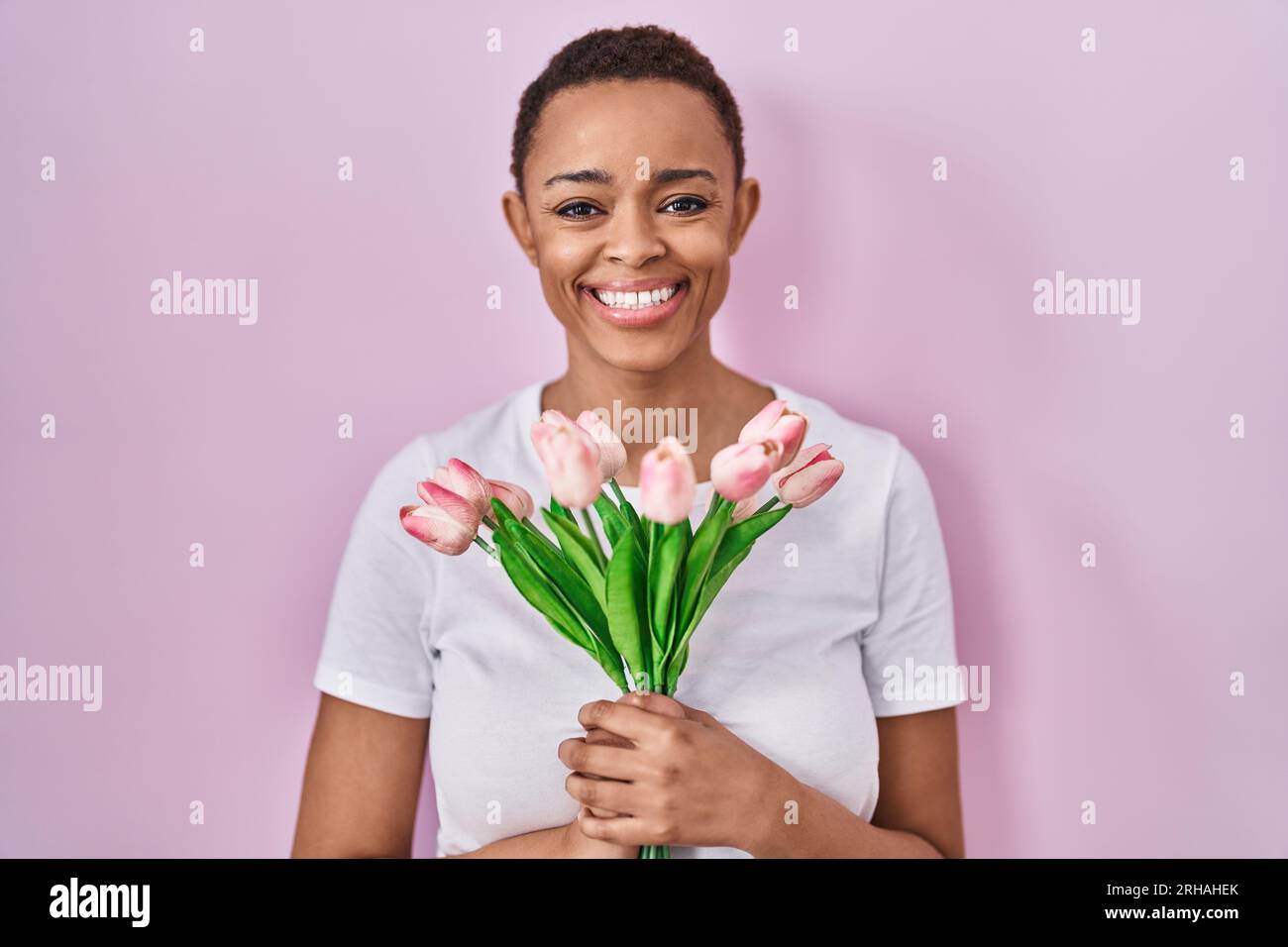 Beautiful african american woman holding bouquet of pink tulips flowers ...