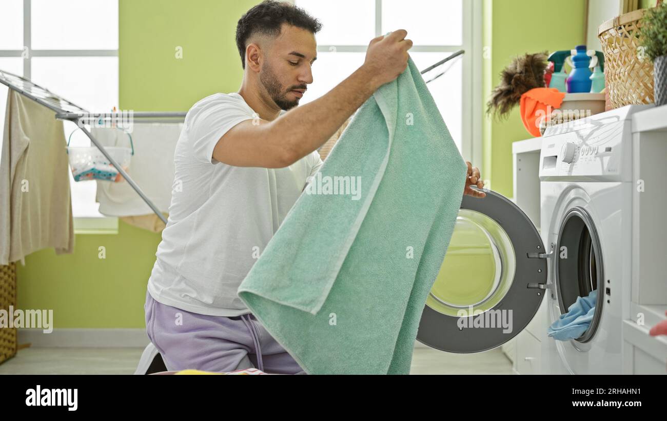 Young arab man washing clothes at laundry room Stock Photo - Alamy