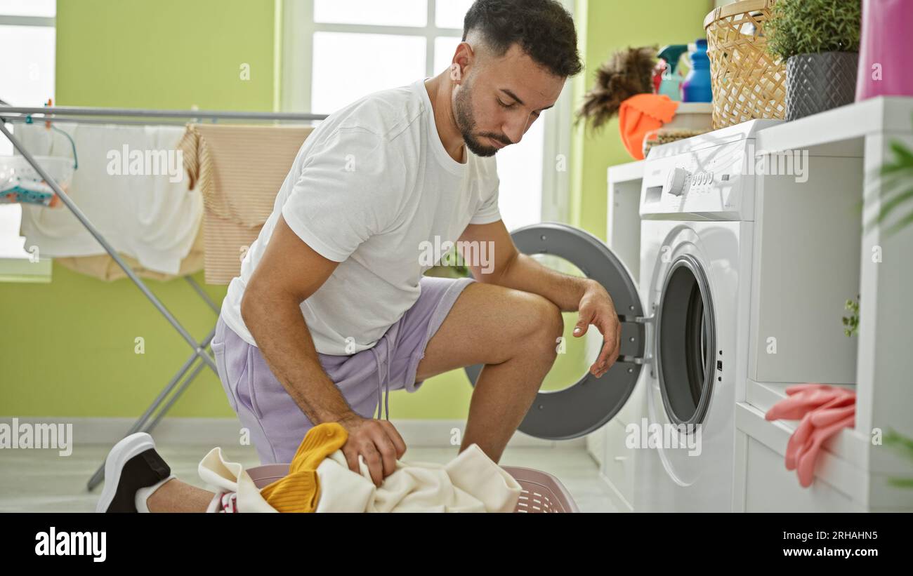 Young arab man washing clothes at laundry room Stock Photo - Alamy