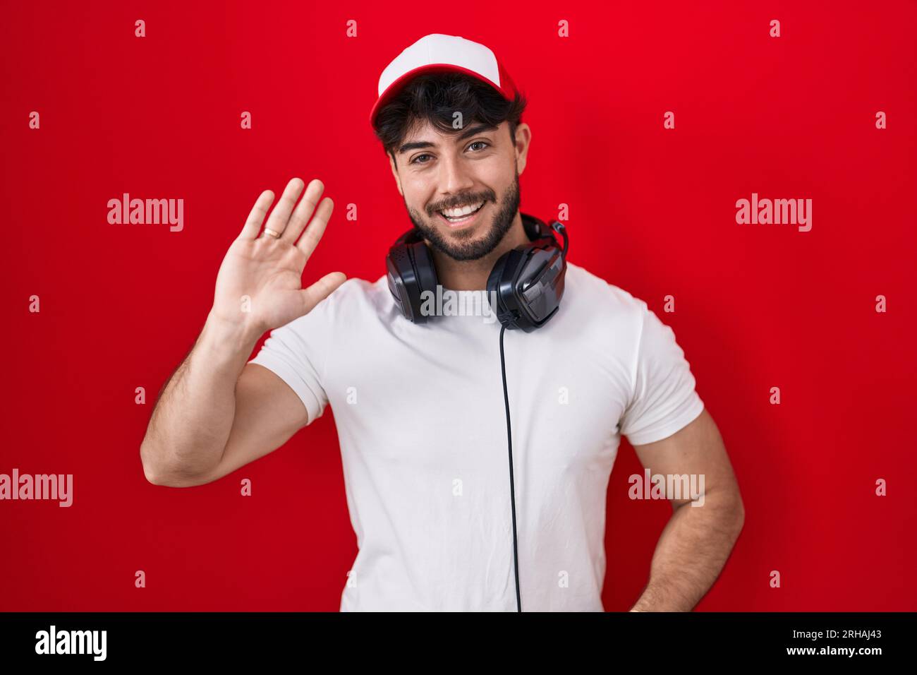 Hispanic man with beard wearing gamer hat and headphones waiving saying ...