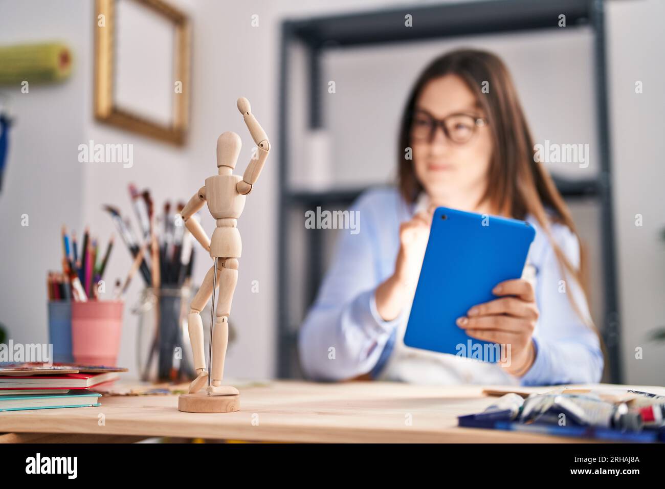 Young woman artist using touchpad drawing manikin on touchpad at art ...