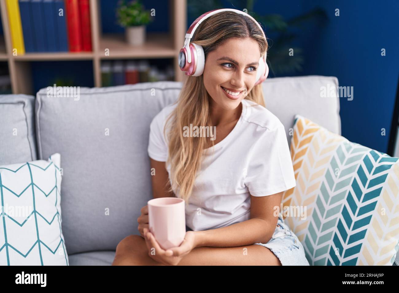 Young blonde woman listening to music drinking coffee at home Stock ...