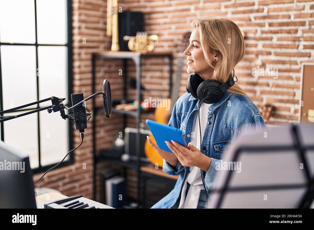 Young blonde woman artist singing song using touchpad at music studio ...