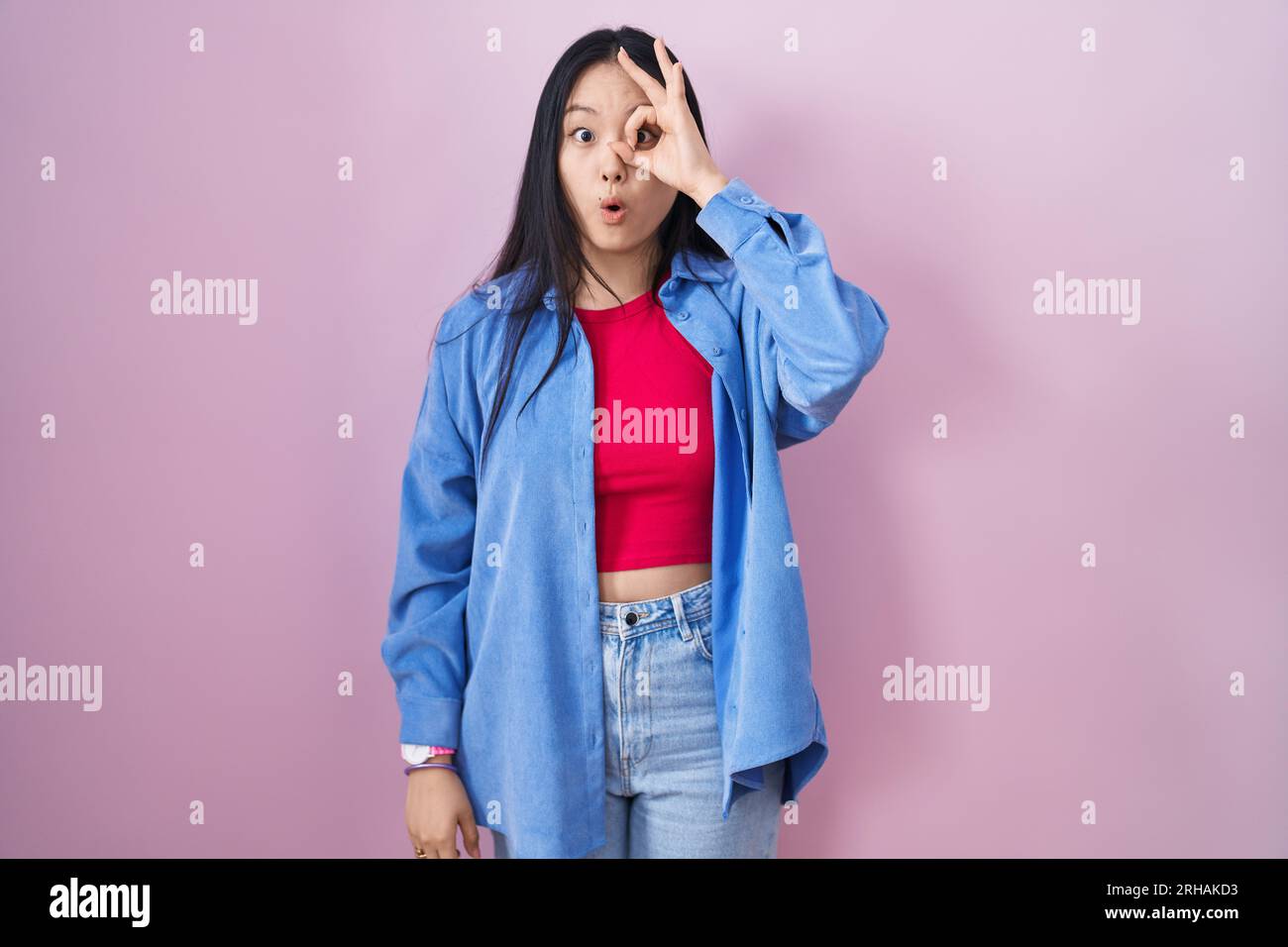 Young asian woman standing over pink background doing ok gesture ...