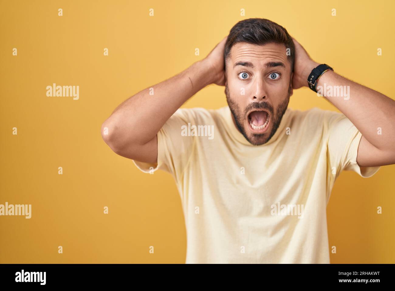 Handsome hispanic man standing over yellow background crazy and scared ...