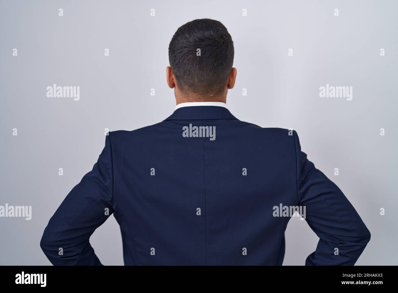 Handsome hispanic man wearing suit and tie standing backwards looking ...