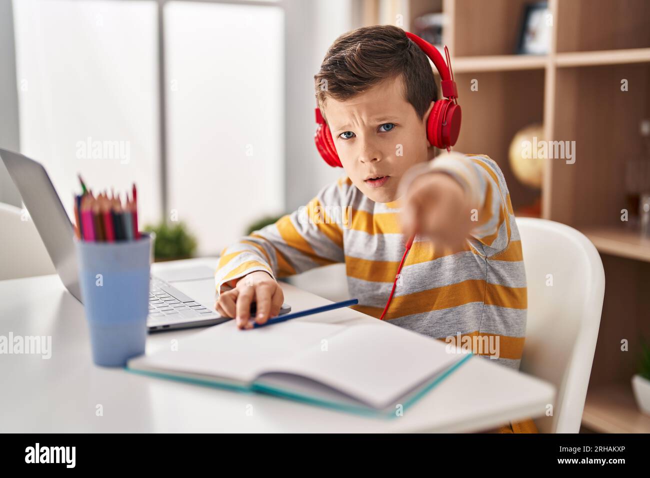 Young caucasian kid doing homework at home pointing with finger to the ...