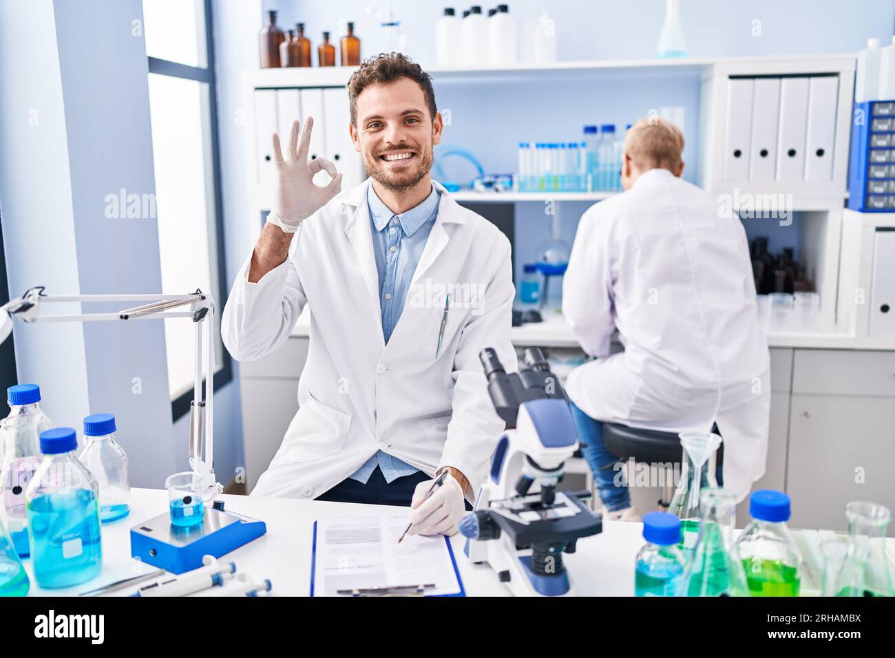 Hispanic man and woman working at scientist laboratory doing ok sign ...