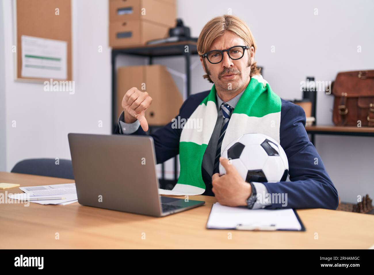 Caucasian man with mustache working at the office supporting football ...