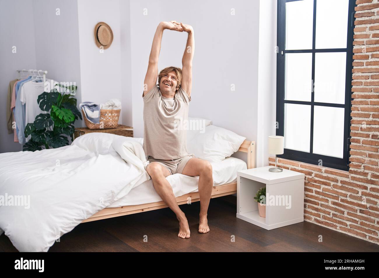 Young man waking up stretching arms at bedroom Stock Photo - Alamy