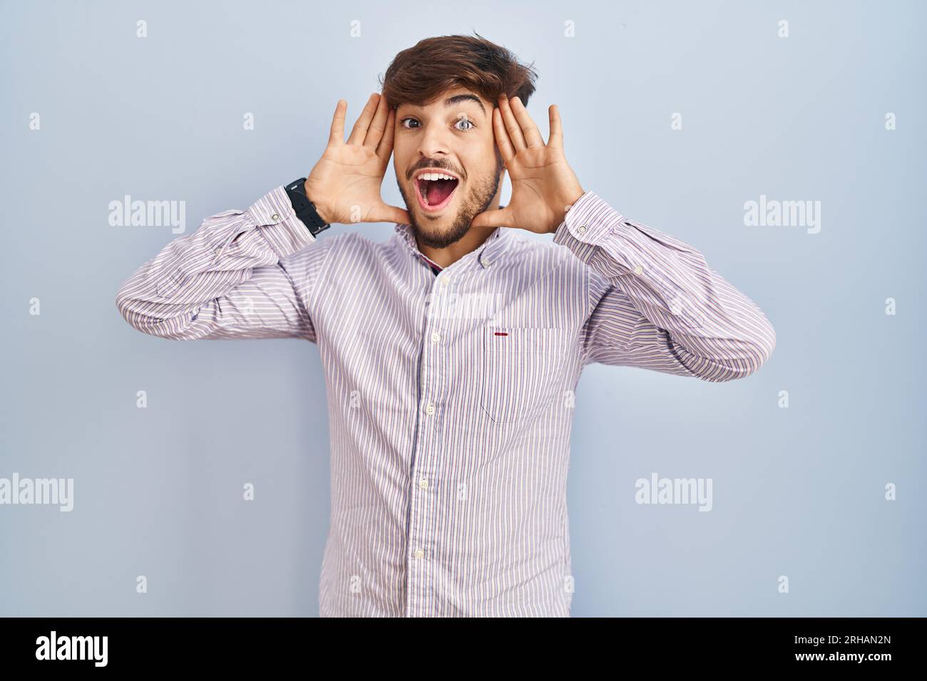 Arab man with beard standing over blue background smiling cheerful ...