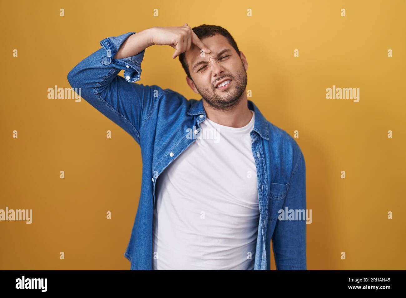 Hispanic man standing over yellow background pointing unhappy to pimple ...
