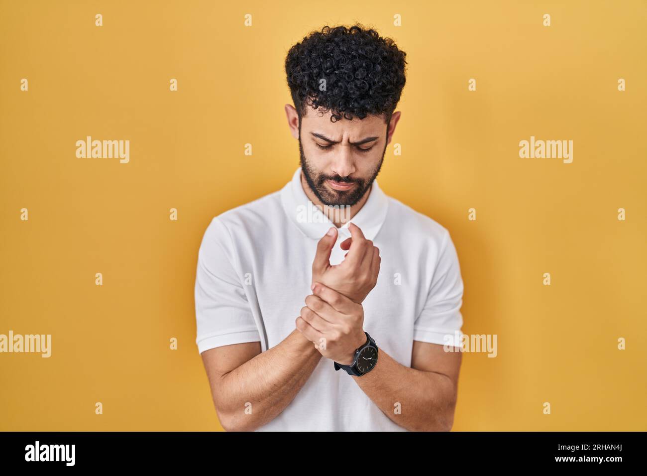 Arab man standing over yellow background suffering pain on hands and ...