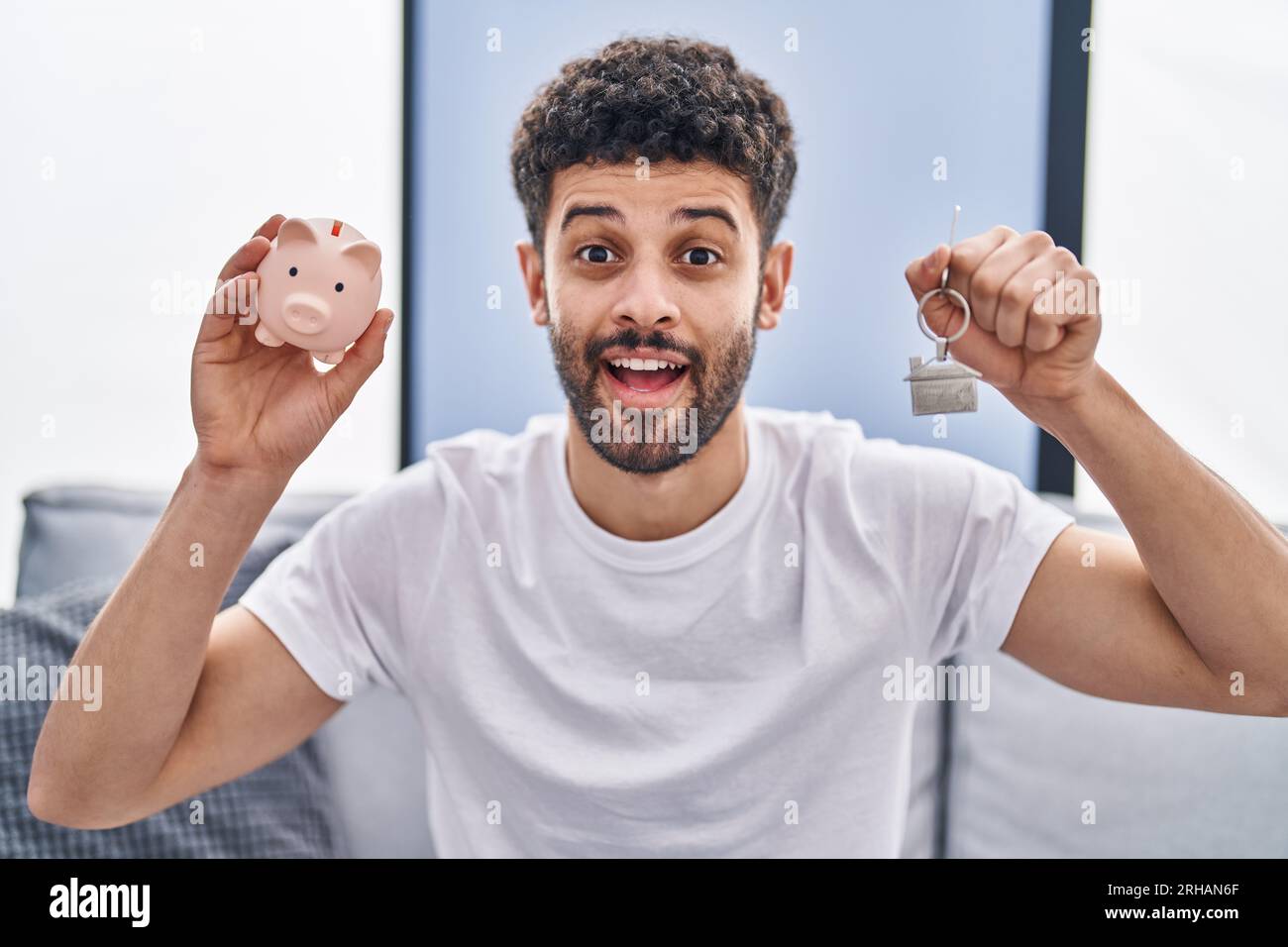Arab man holding piggy bank and house keys celebrating crazy and amazed ...