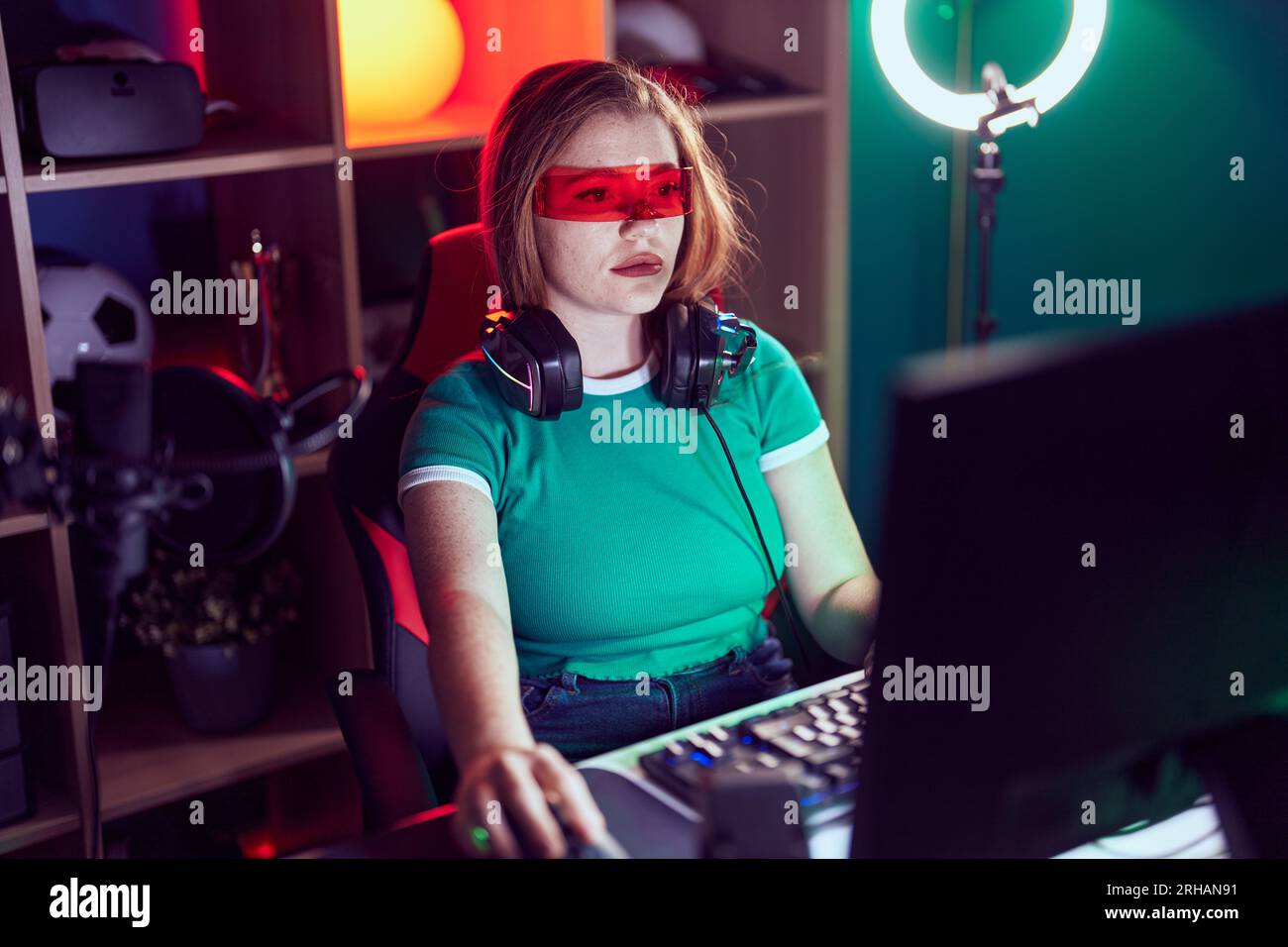 Young redhead woman streamer playing video game using virtual reality ...