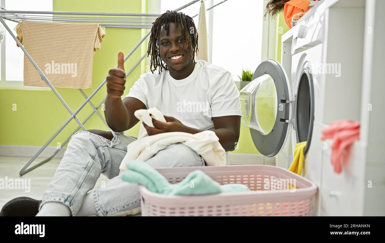 African american man washing clothes doing thumb up gesture at laundry ...