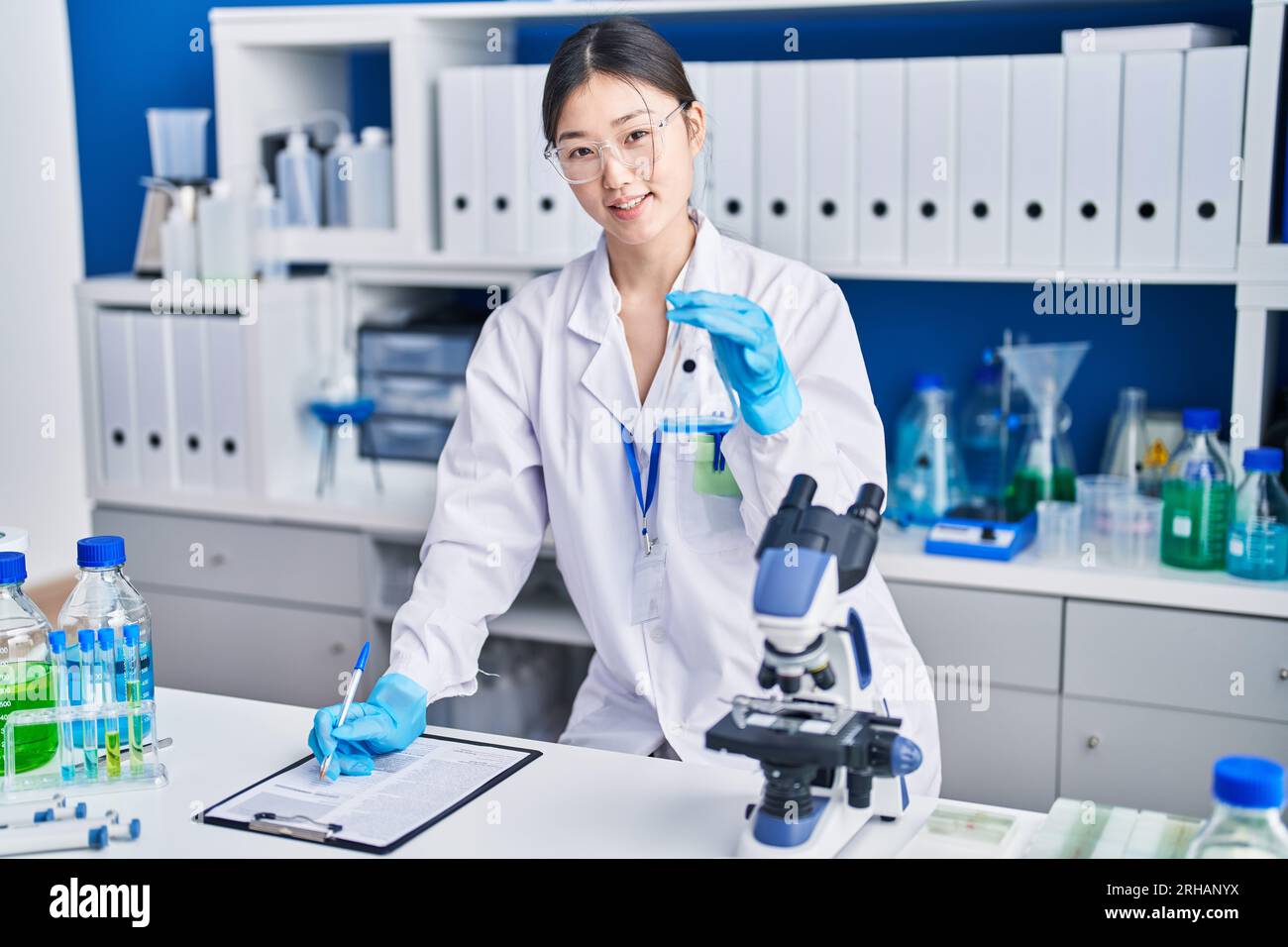 Chinese woman scientist measuring liquid writing on document at ...