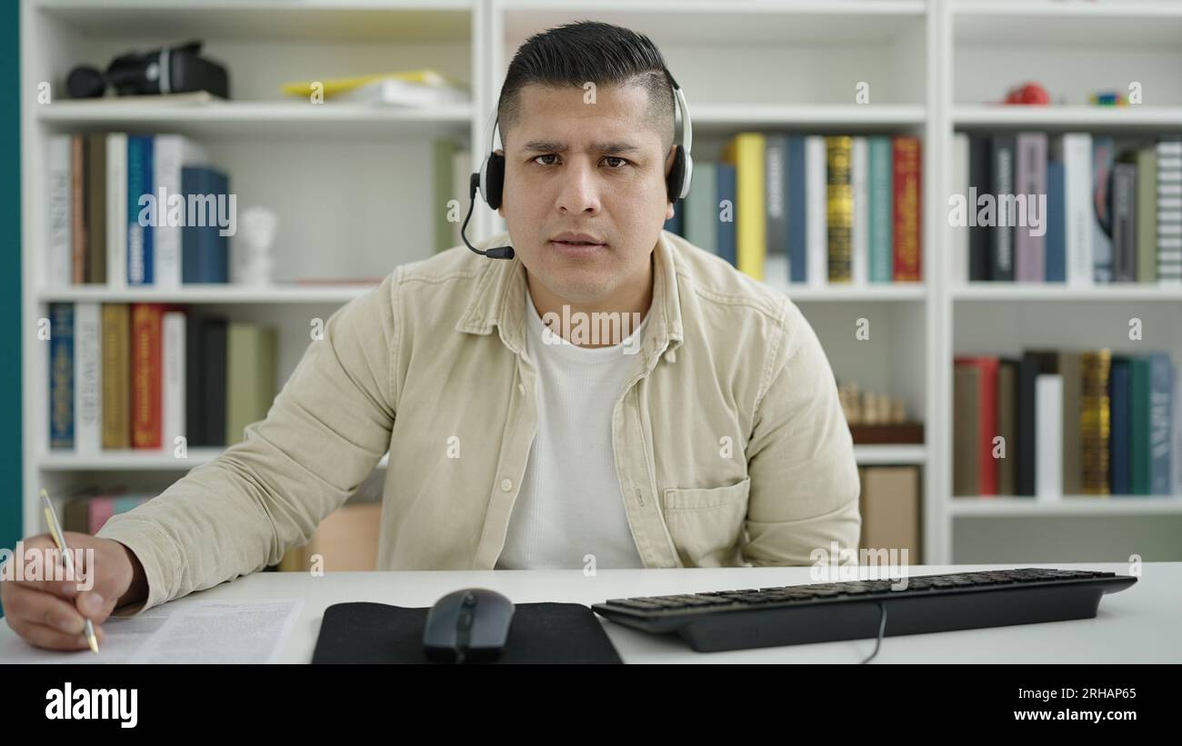 Young hispanic man student having video call writing on document at ...