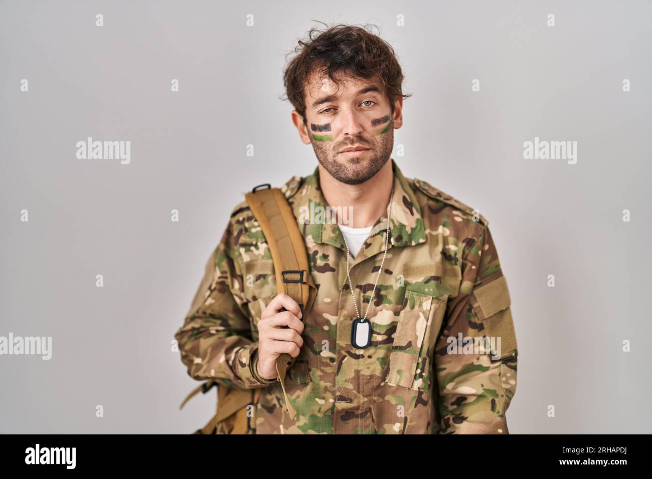 Hispanic young man wearing camouflage army uniform looking sleepy and ...