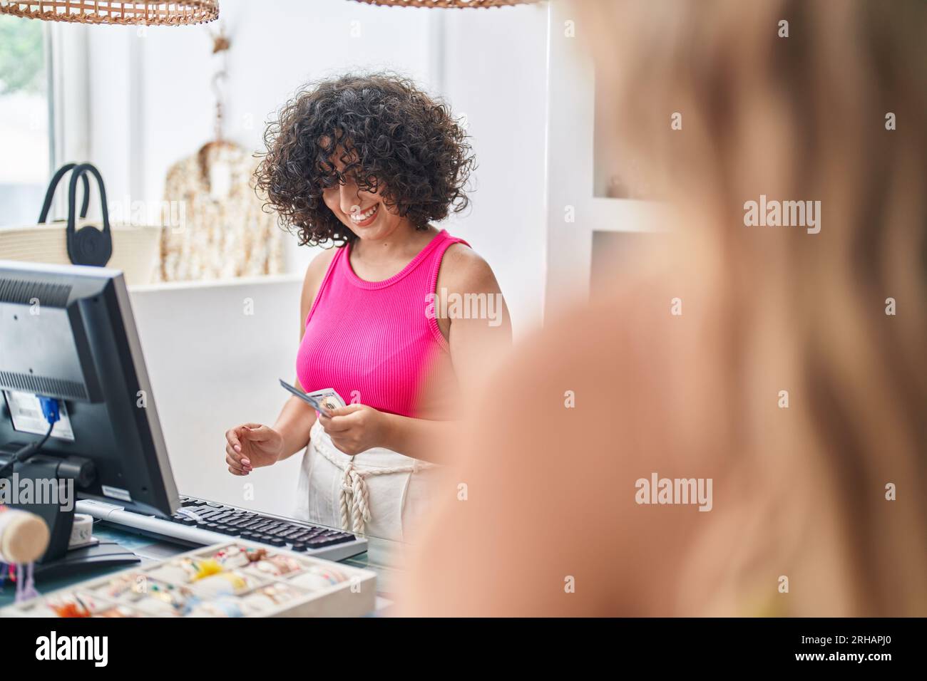 Young middle eastern woman shop assistant holding dollars at clothing ...
