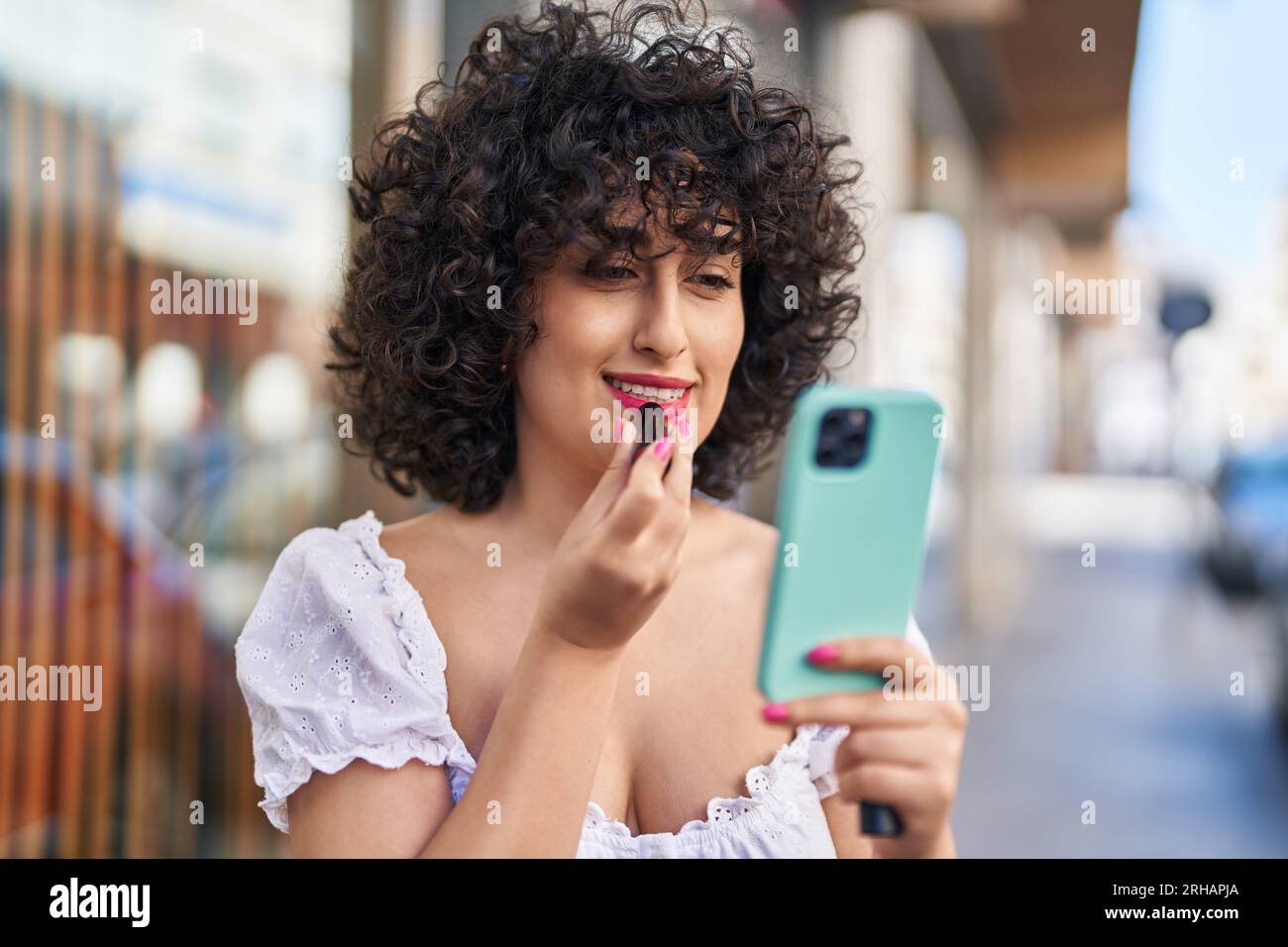 Young middle east woman makeup lips looking smartphone at street Stock ...