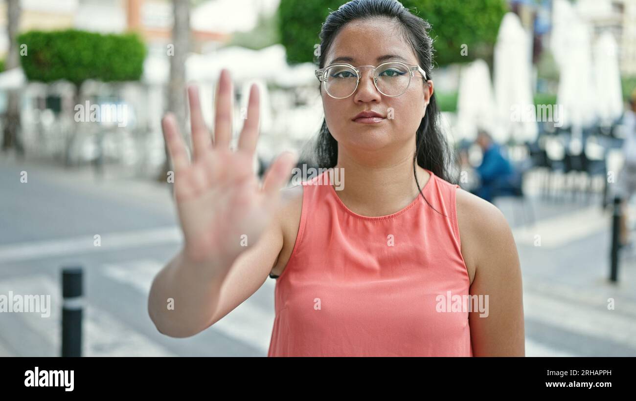 Young chinese woman doing stop gesture with hand at street Stock Photo ...