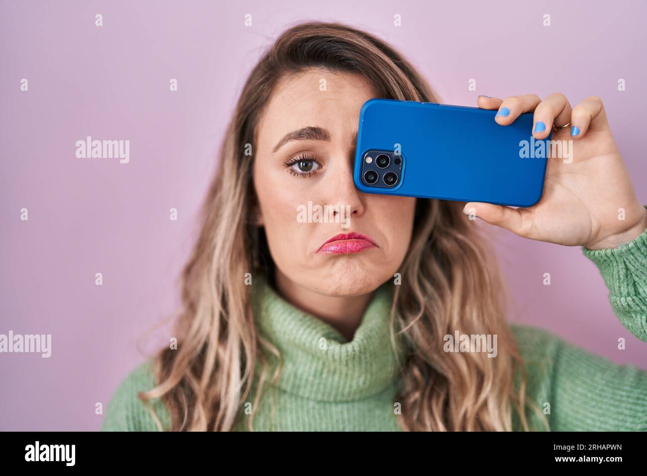 Young caucasian woman covering eye with smartphone depressed and worry ...