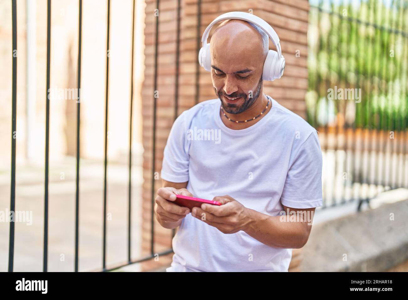 Young bald man smiling confident playing video game at street Stock ...