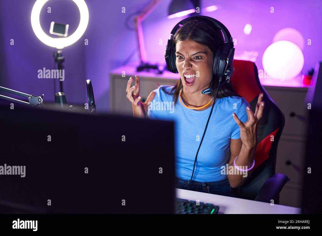 Brunette young woman playing video games crazy and mad shouting and ...