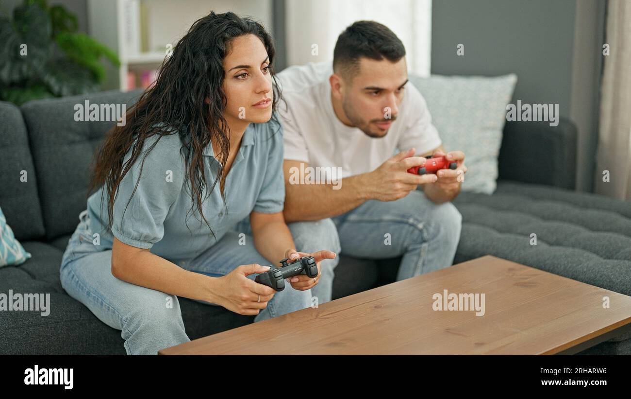 Man and woman couple playing video game sitting on sofa at home Stock ...