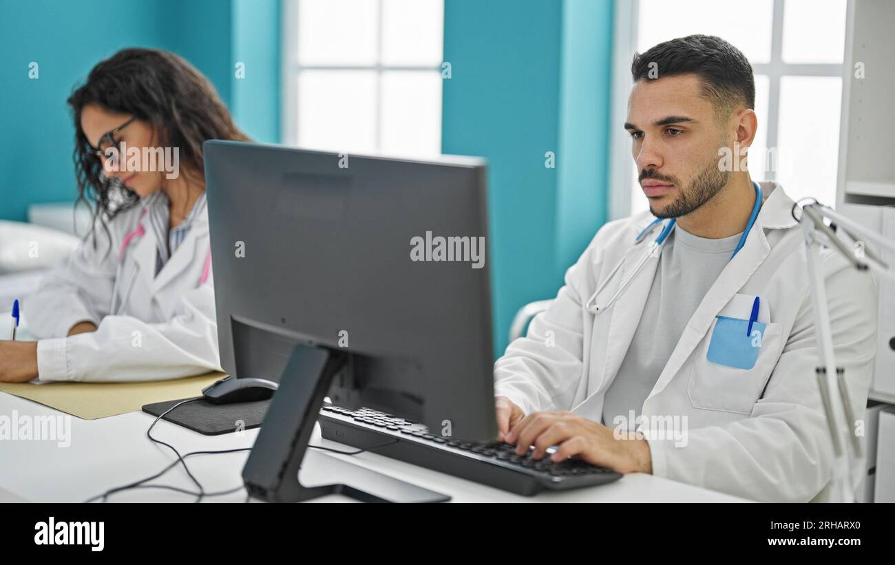 Man and woman doctors using computer taking notes working at the clinic ...